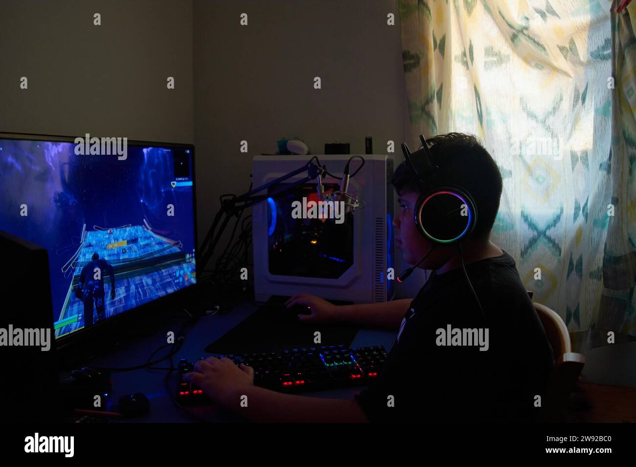 Side View of teenage gamer boy playing video games online on computer ...