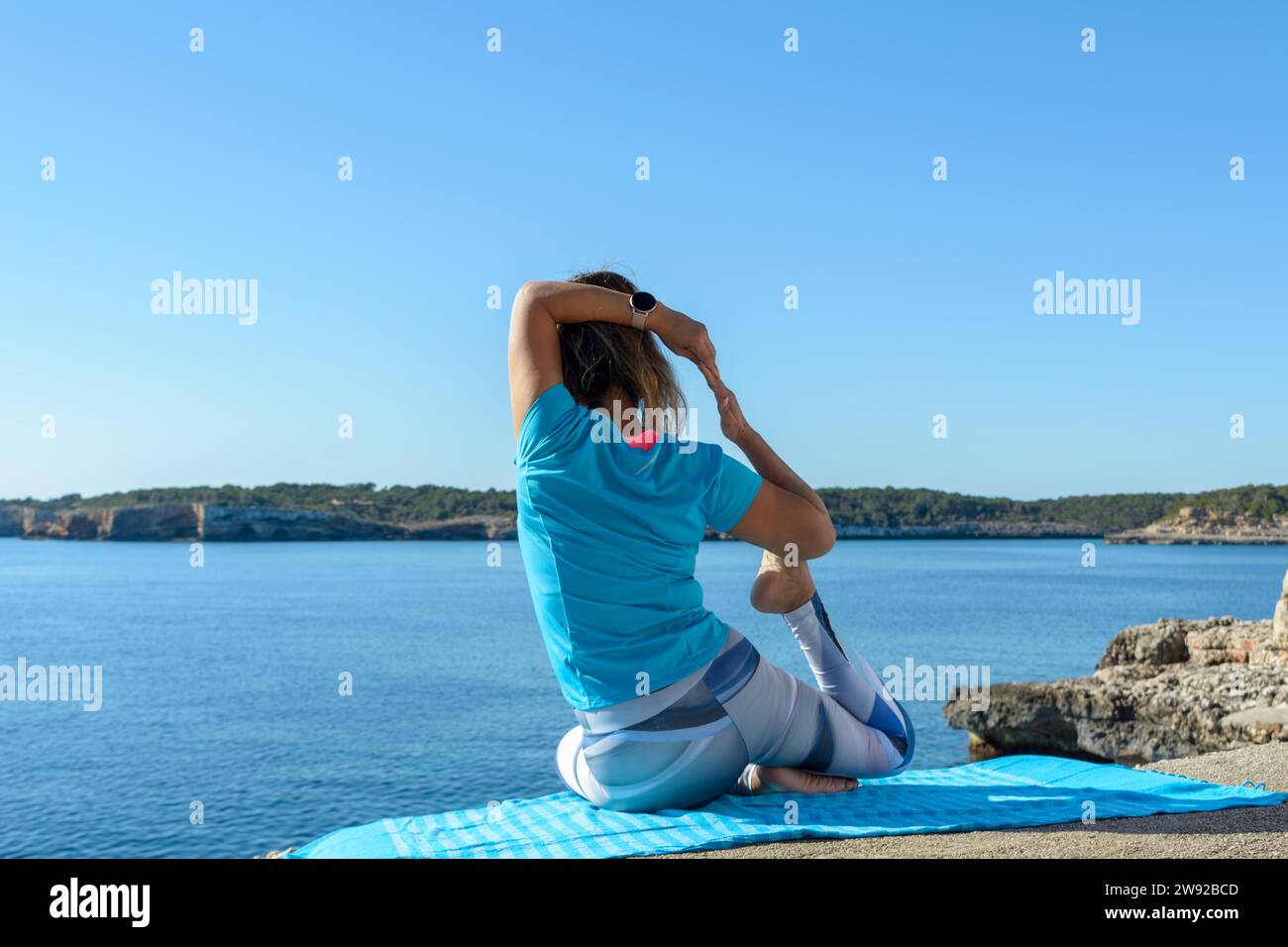 Middle-aged fitness woman outdoors in front of the sea does yoga ...