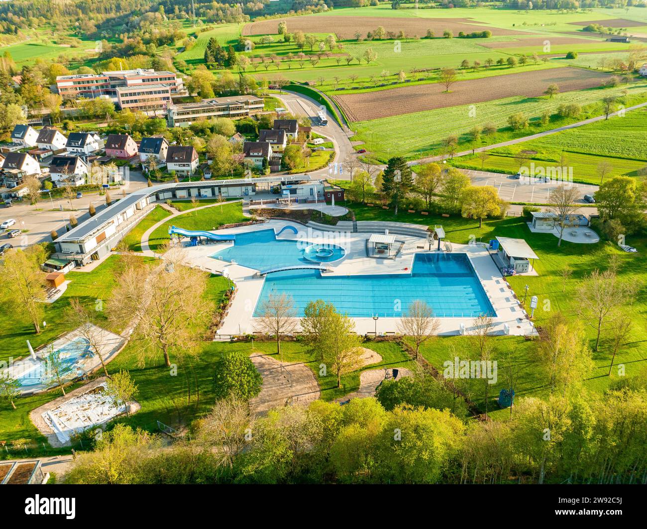 Wide-angle drone view of an outdoor swimming pool surrounded by green ...
