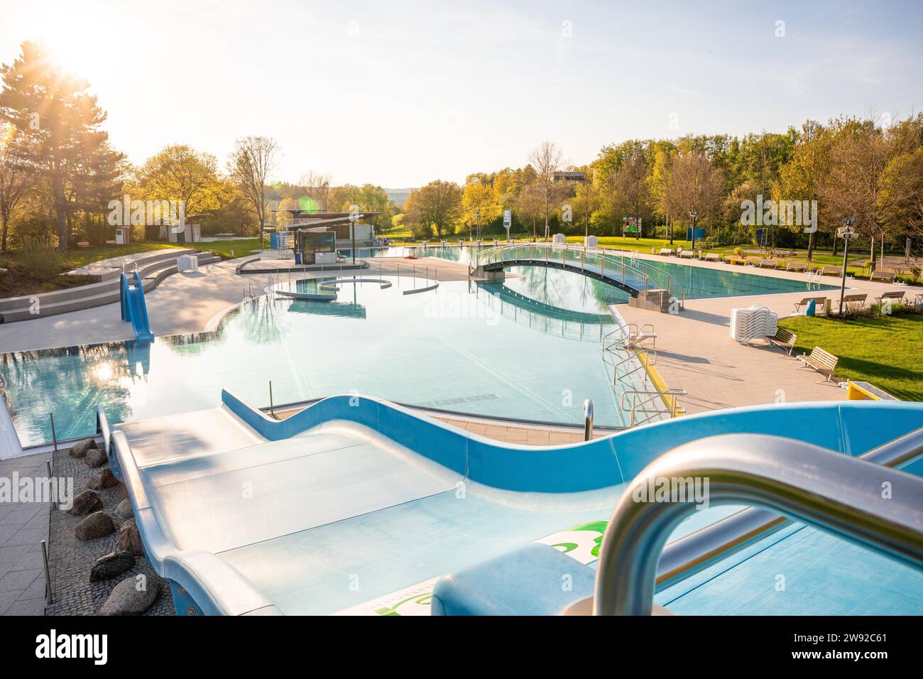 Sunny spring day in a public swimming pool with slides and water basin ...