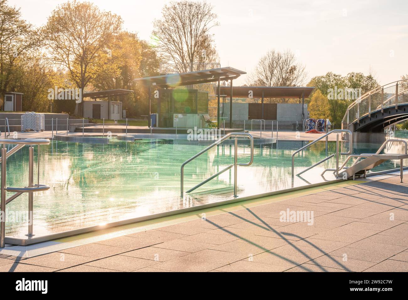 Calm water in an outdoor pool surrounded by railings in low sun, Calw ...