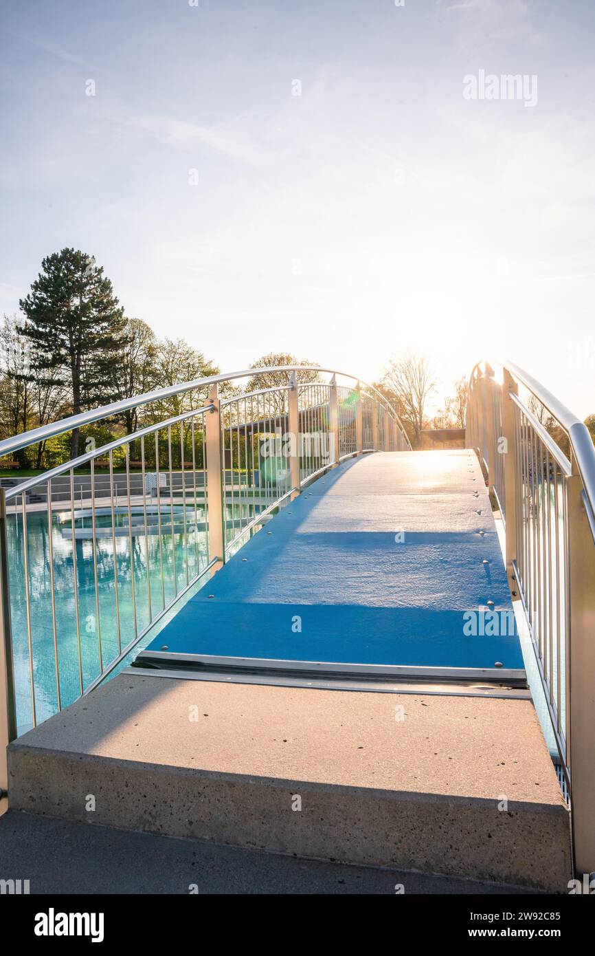 Blue pedestrian bridge over a swimming pool with a clear sky in the ...