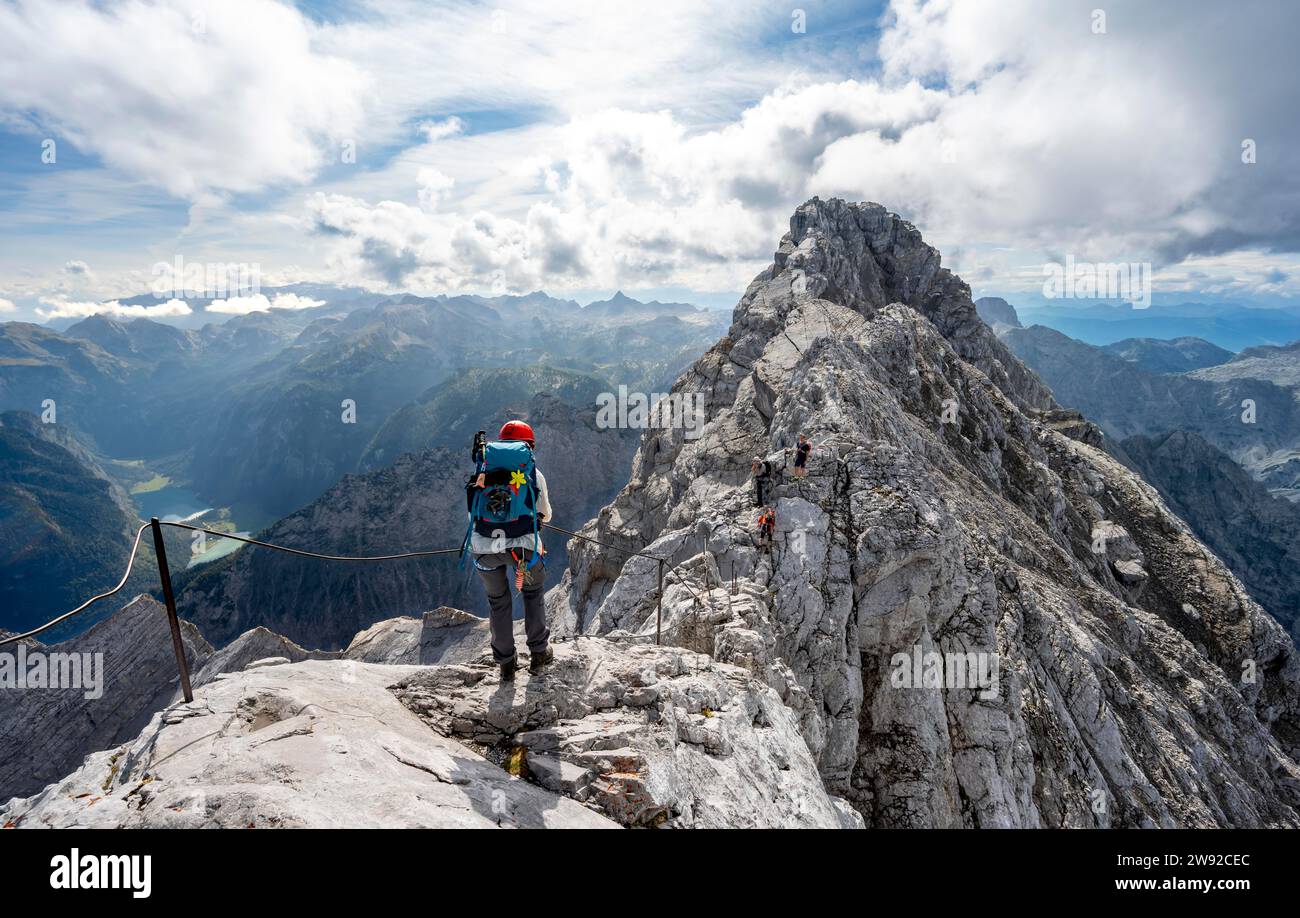 Climber on a via ferrata secured with steel rope, narrow rocky mountain ...