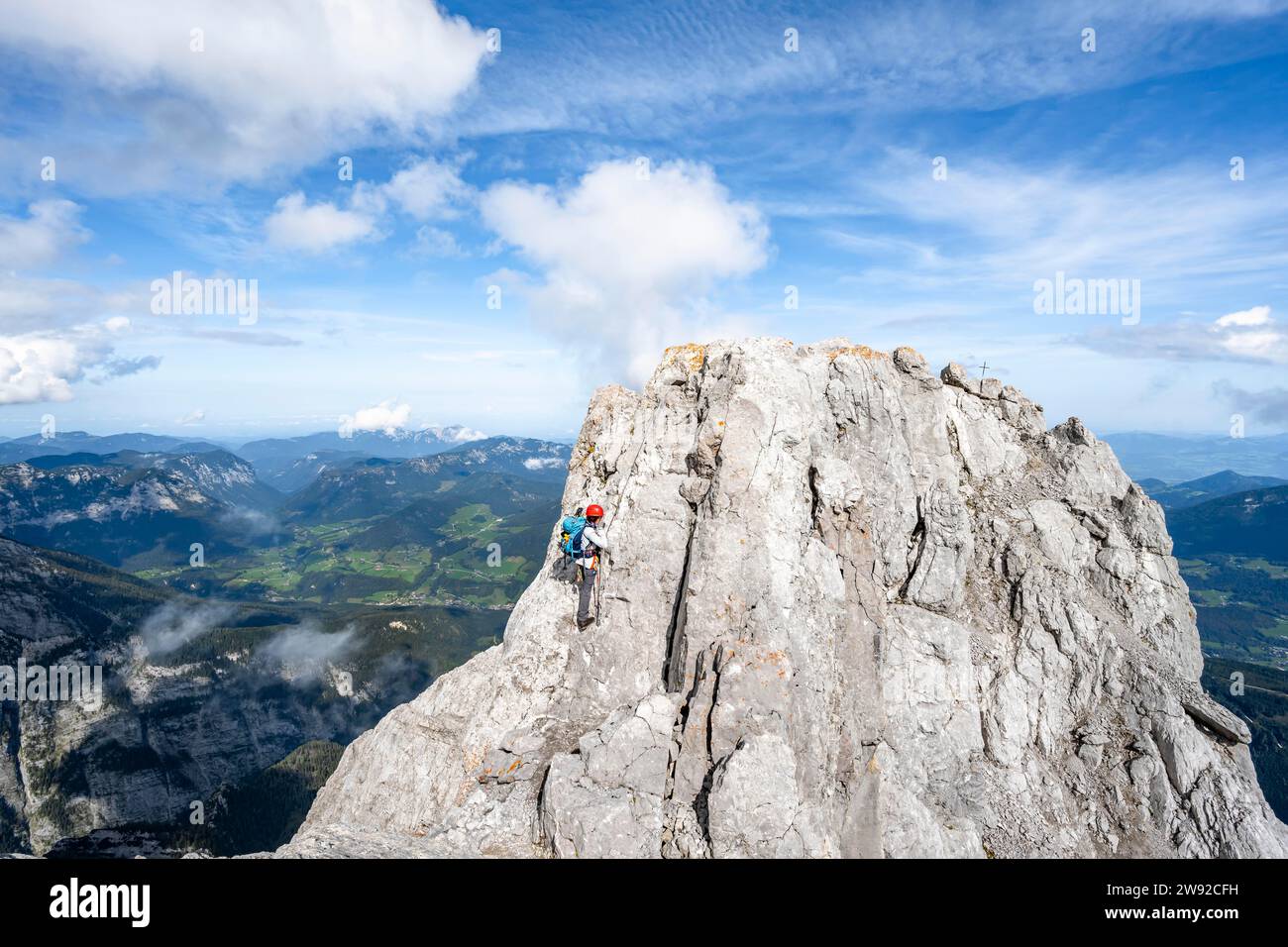 Female mountaineer climbing a via ferrata secured with a steel cable ...