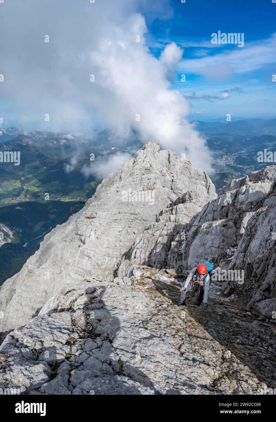 Climber on a via ferrata secured with steel rope, steep rocky mountain ...