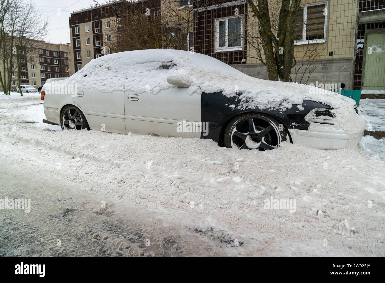 A serene urban street scene exhibits a car concealed under a layer of ...