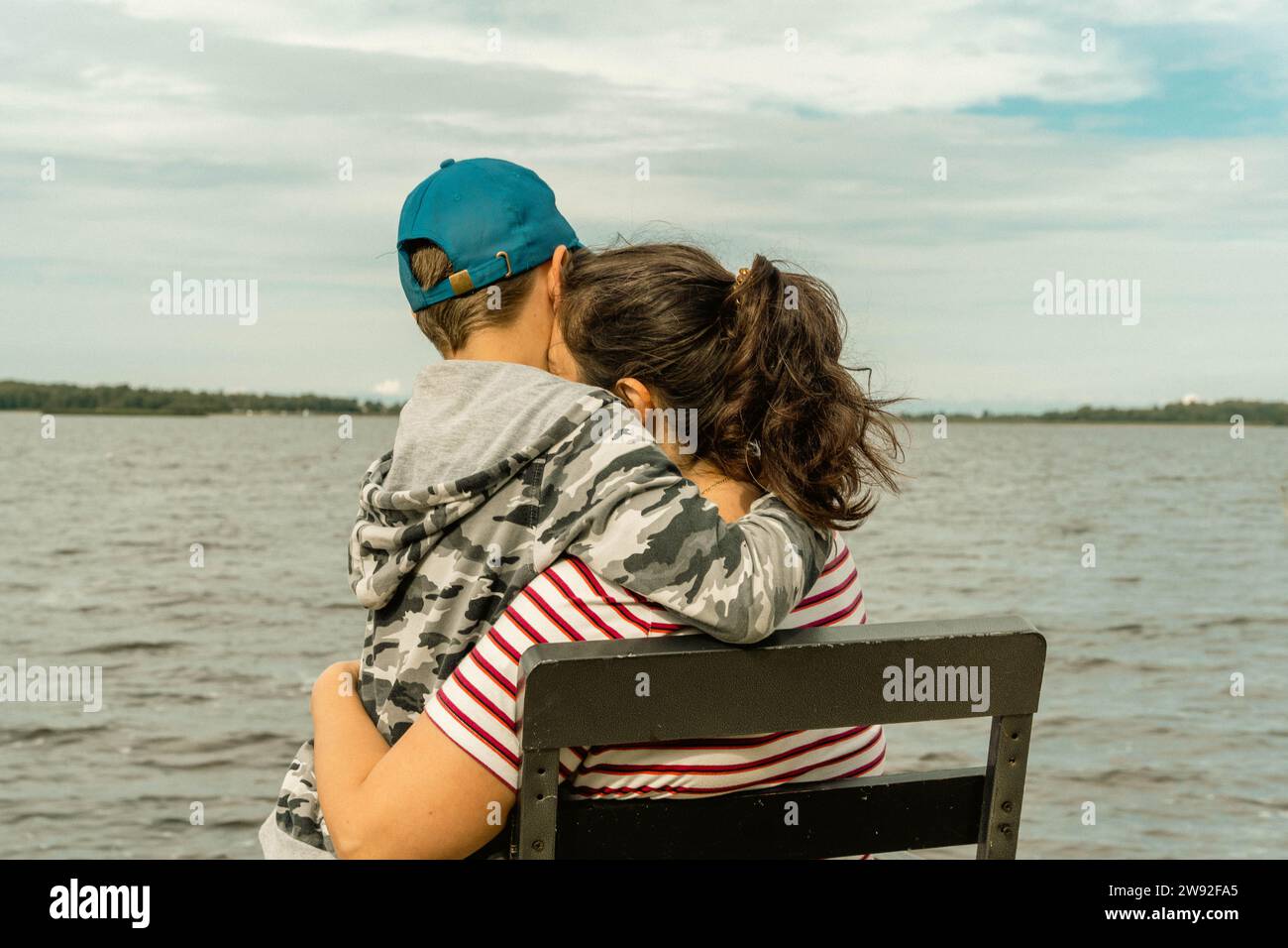 school-age son is embraced by his middle-aged mother, portraying ...