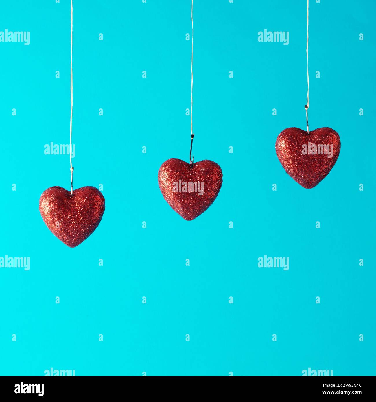 Three red hearts in fish hooks on a blue background. Love concept Stock ...