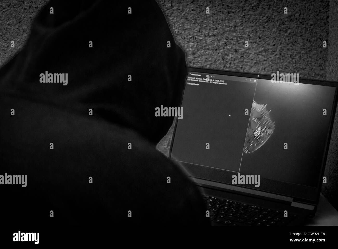 Man looked like hacker in a hood sitting in the front of laptop ...