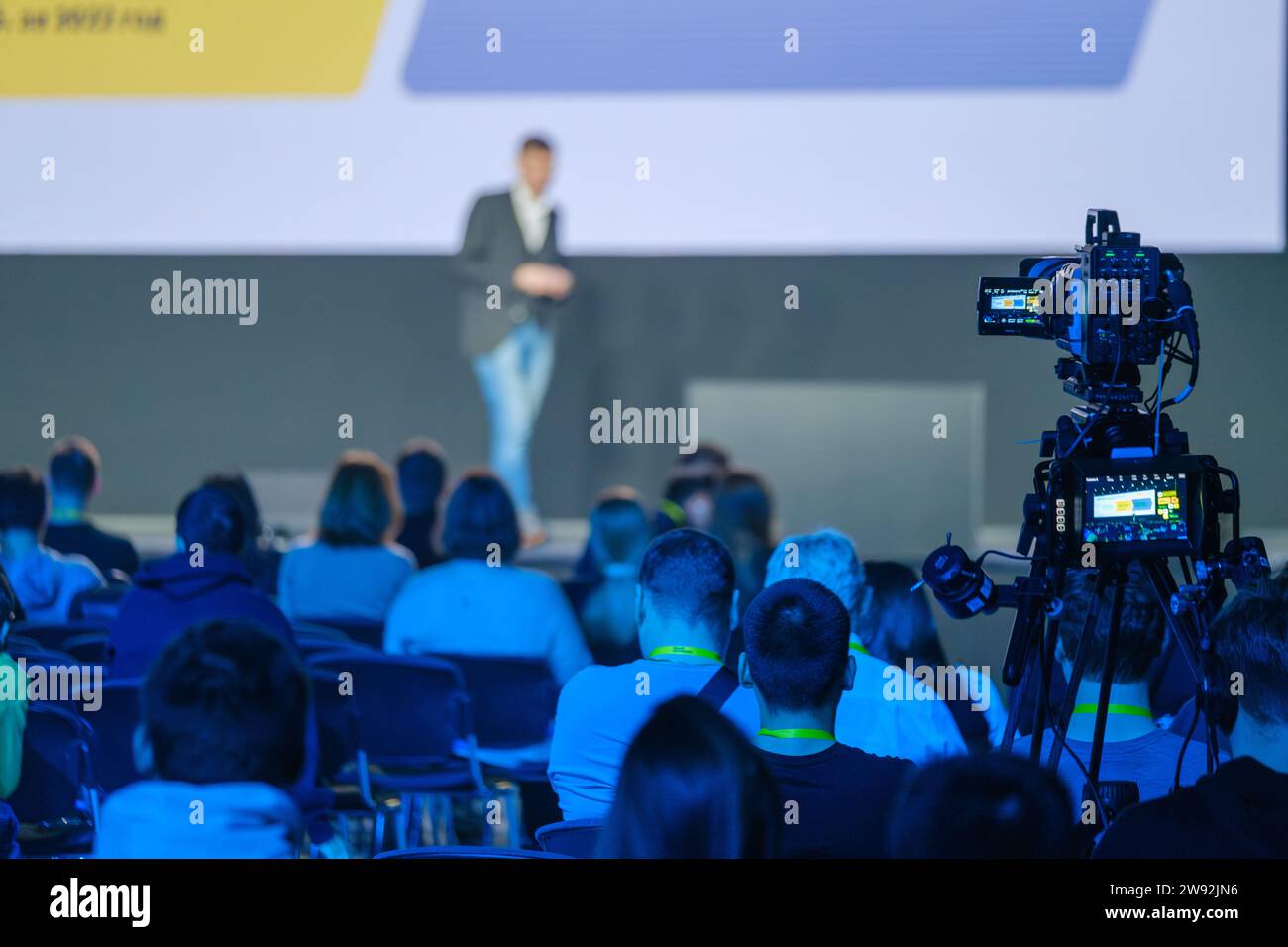 Video camera recording male speaker giving presentation in illuminated ...