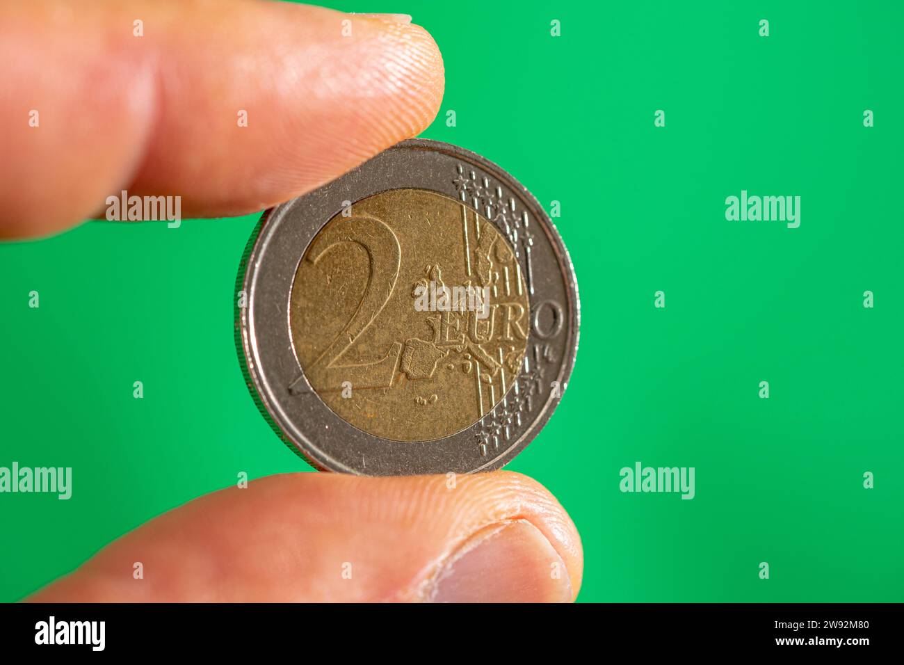 2 euro coin face held between thumb and index finger Stock Photo - Alamy