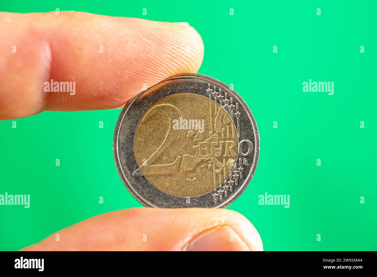 2 euro coin face held between thumb and index finger Stock Photo - Alamy