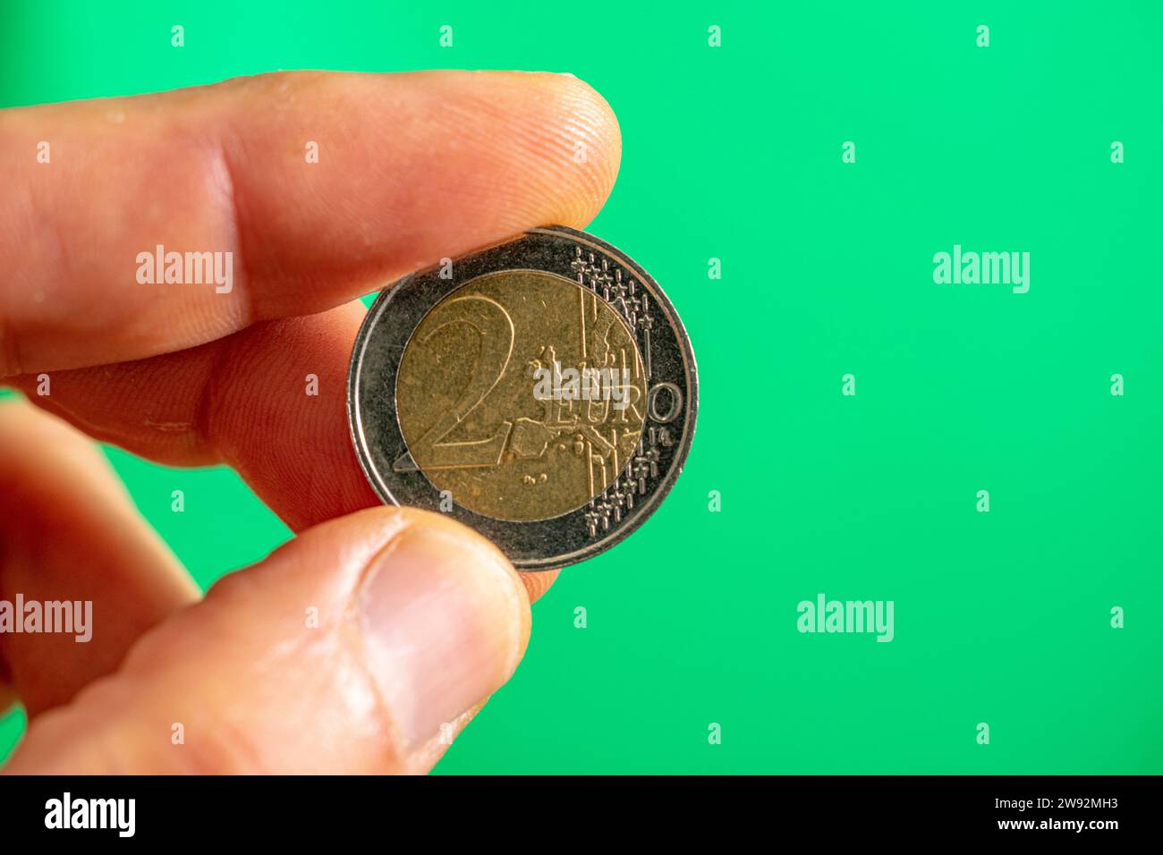 2 euro coin face held between thumb and index finger Stock Photo - Alamy