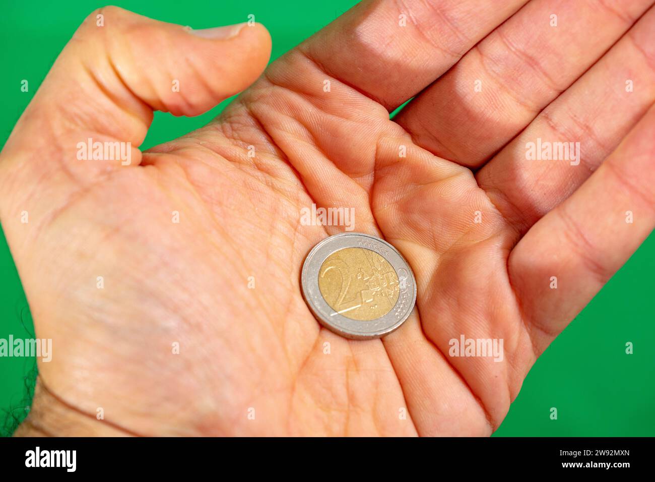 coin face of 2 euro on the palm. green background Stock Photo - Alamy