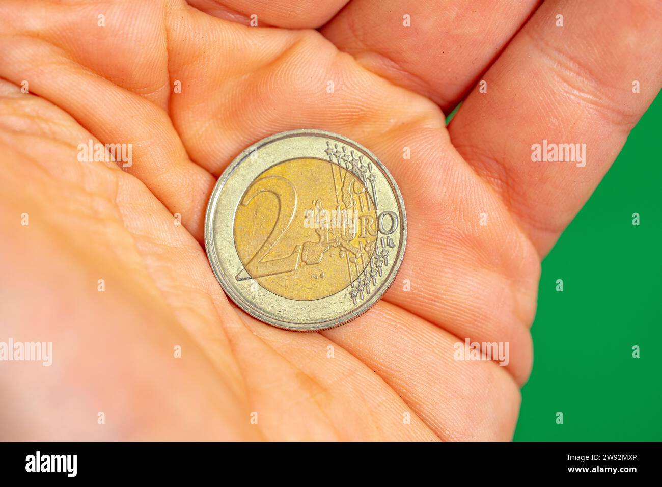 coin face of 2 euro on the palm. green background Stock Photo - Alamy