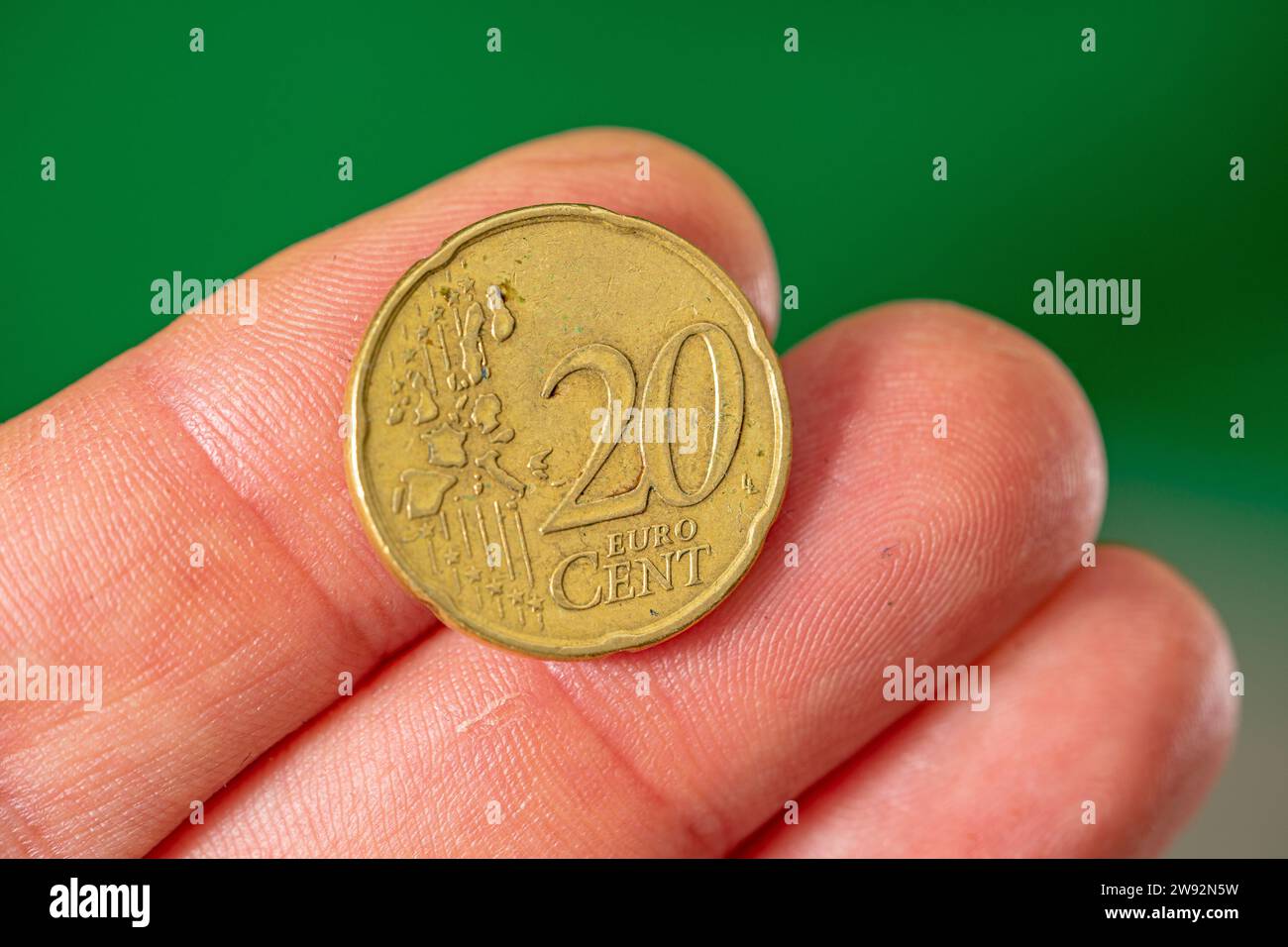 20 euro cent coin face held between thumb and index finger Stock Photo ...