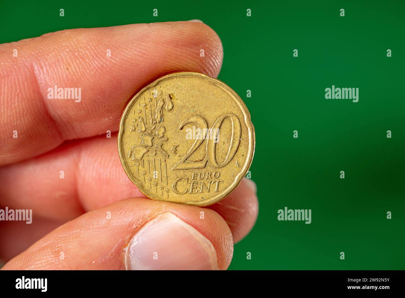 20 euro cent coin face held between thumb and index finger Stock Photo ...