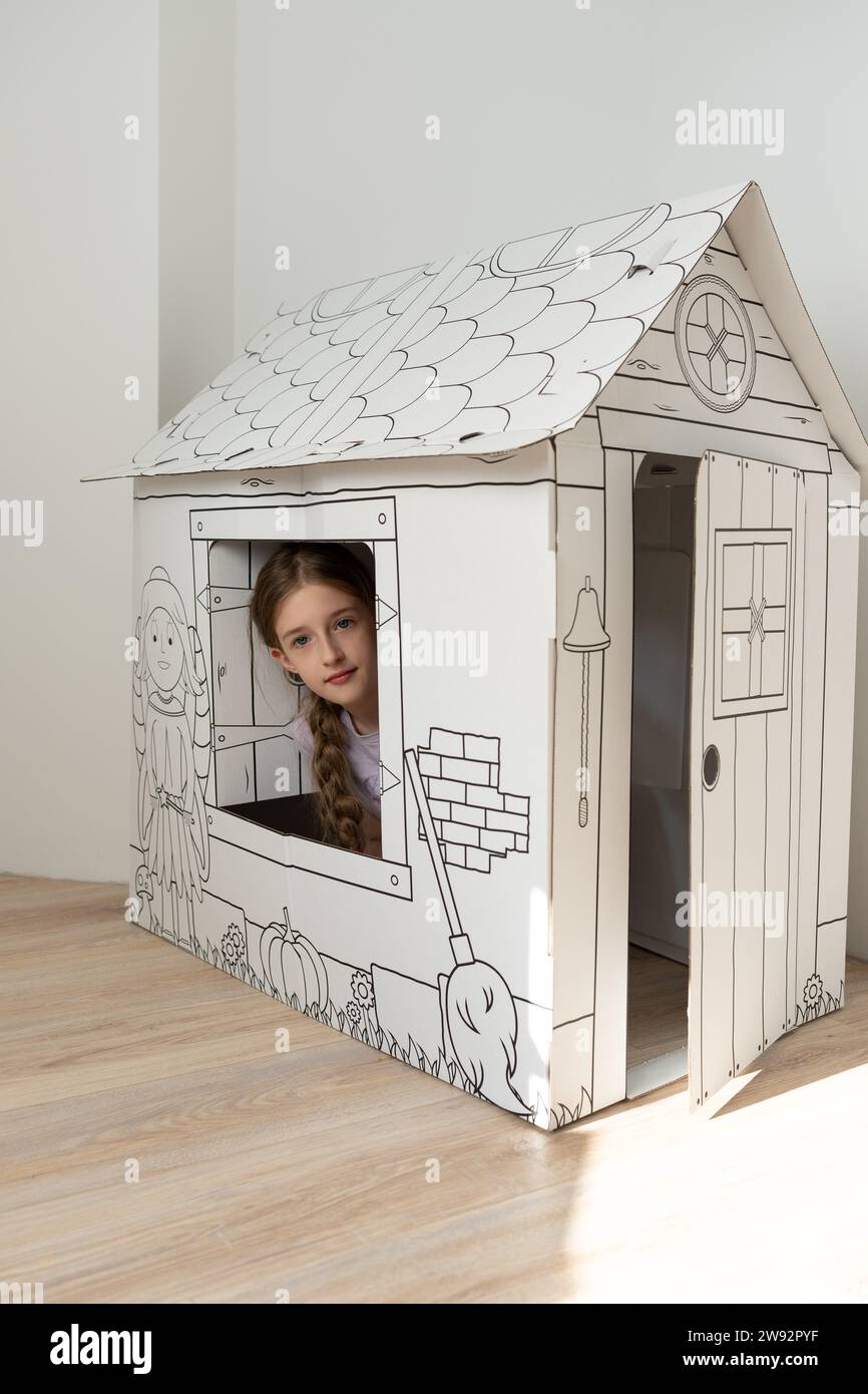 A child and a paper playhouse. Paper house for drawing. Children's toys ...