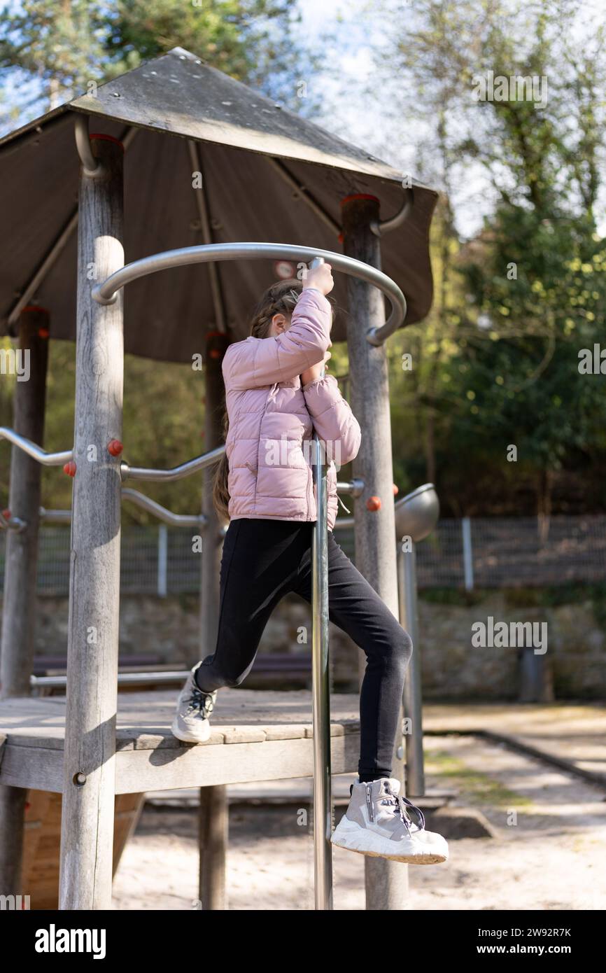 The little girl is sliding down the tube at the playground. The child ...