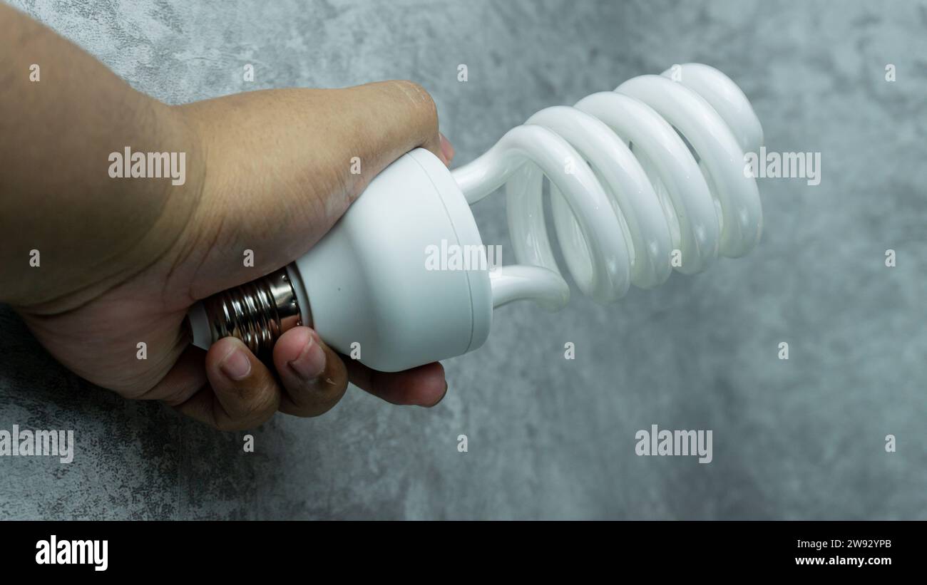 Spiral shaped bulb held in hand on gray background with concrete ...