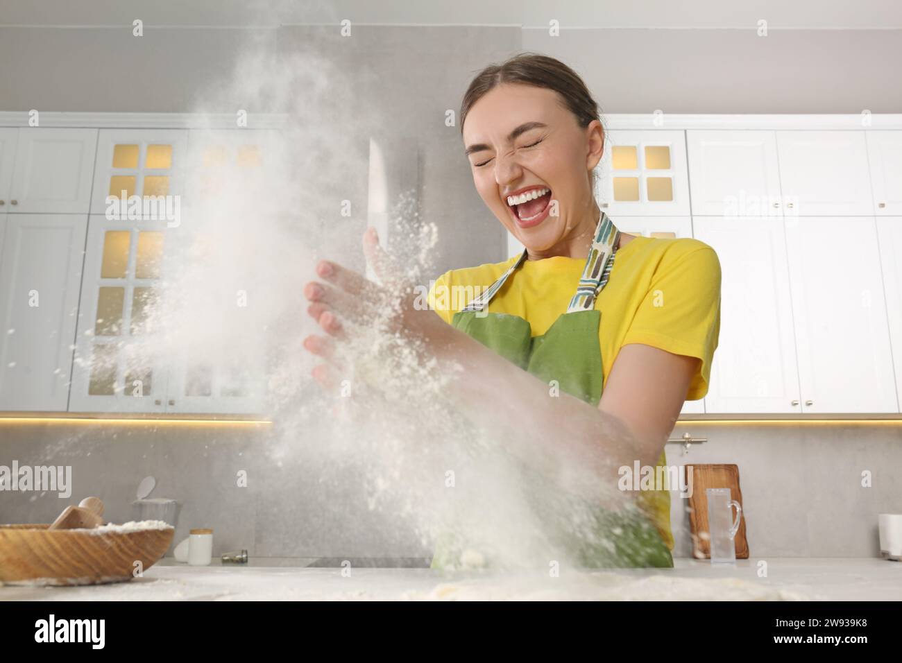 Funny woman clapping floury hands over messy table in kitchen Stock ...