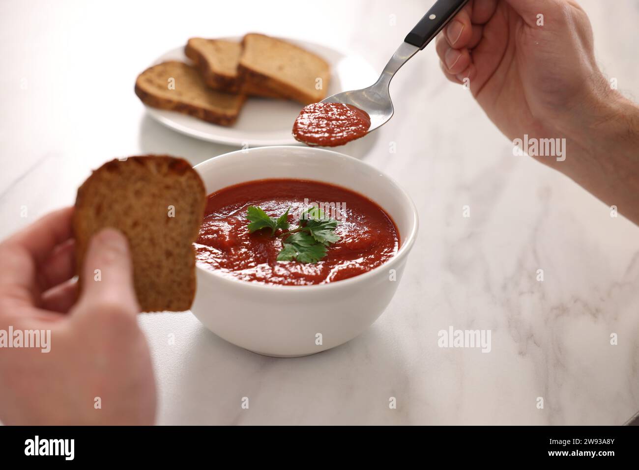 Man eating delicious tomato soup at light marble table, closeup Stock ...