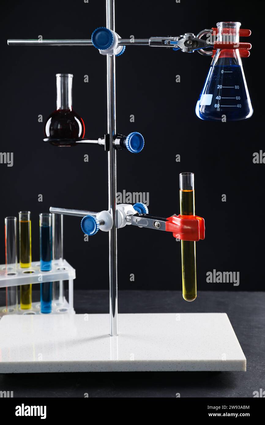 Retort stand and laboratory glassware with liquids on table against ...