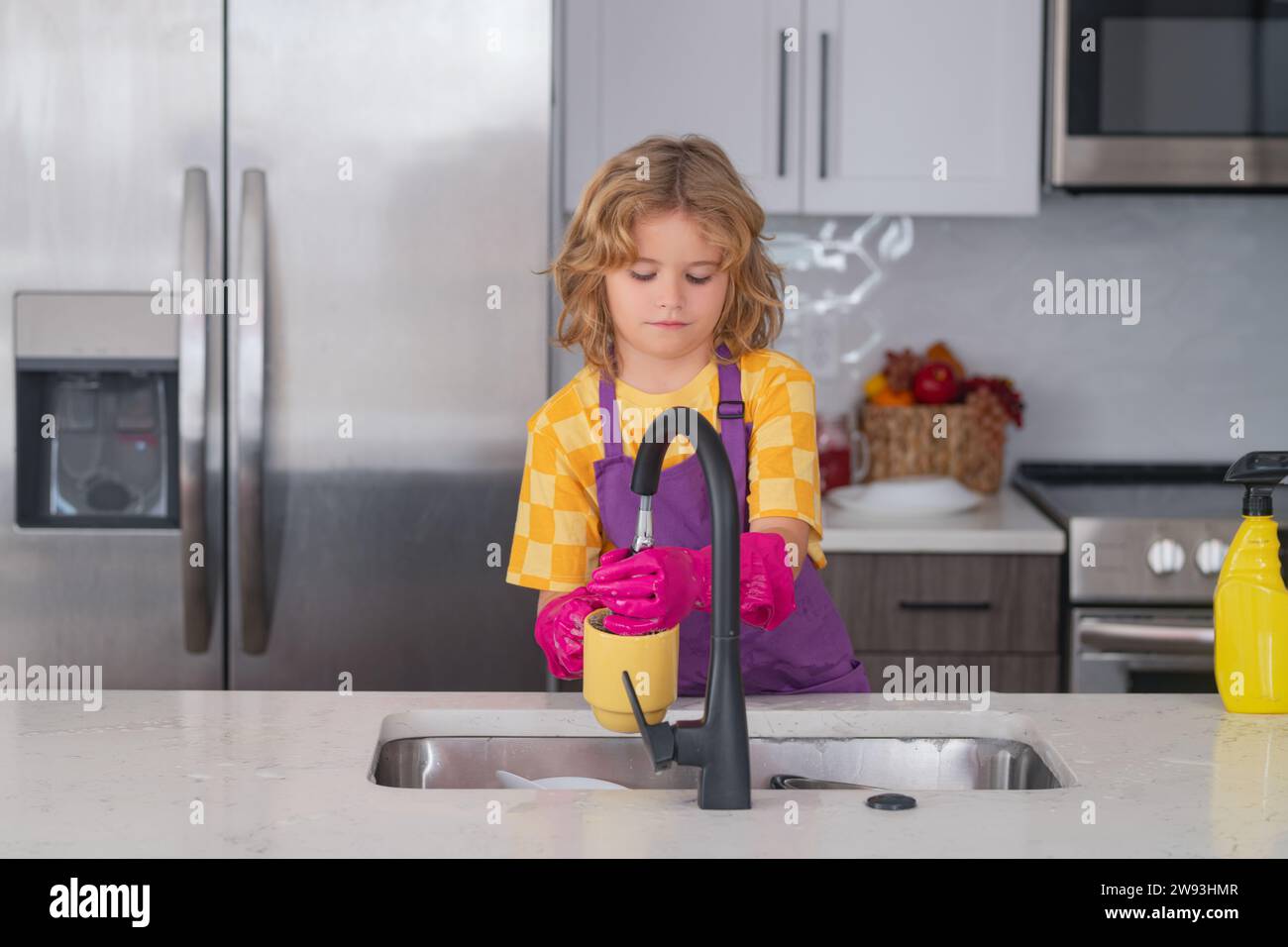 Portrait of child cleaning in the kithen. Child housekeeper washing the ...