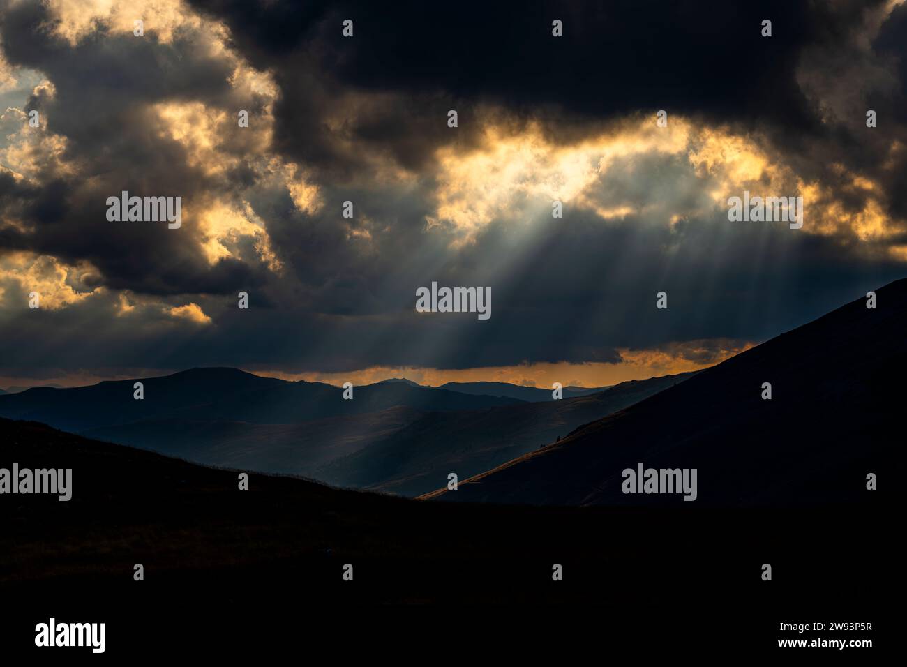 Dark mountain background. Dramatic sky with the rays of the setting sun ...