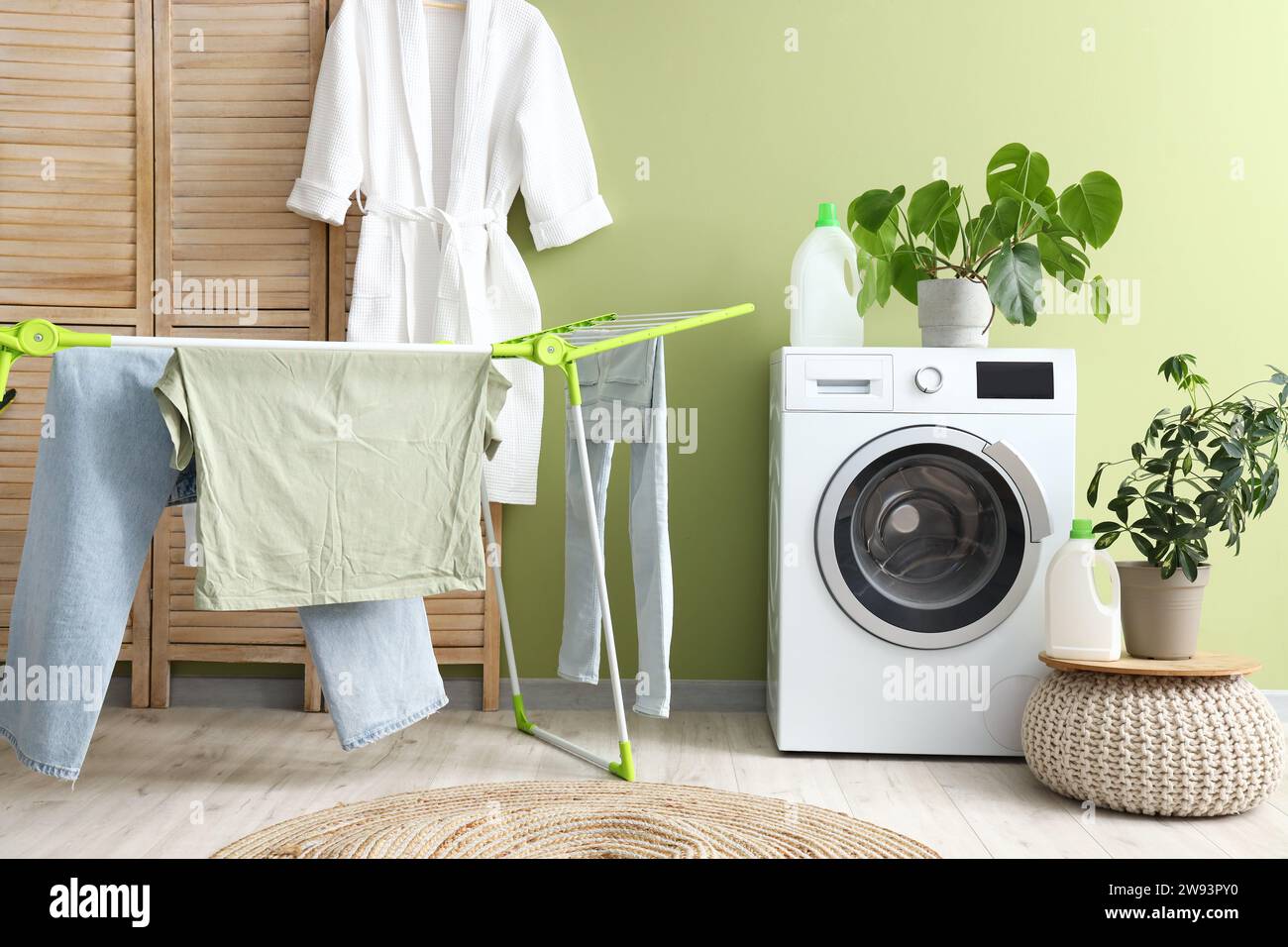 Laundry room interior with washing machine and clothes on drying rack ...