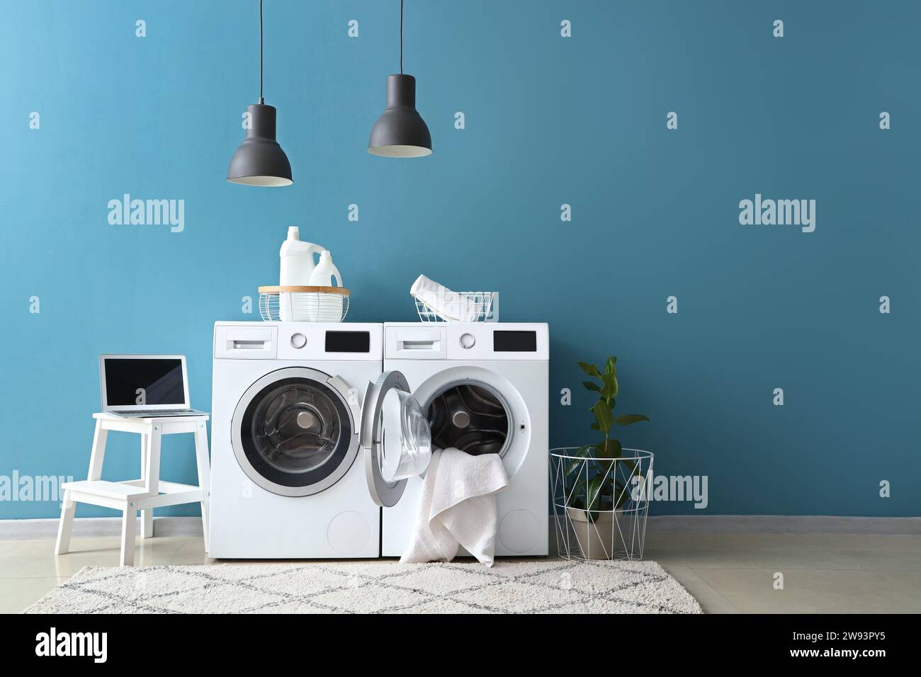 Interior of modern laundry room with washing machines and laptop near ...