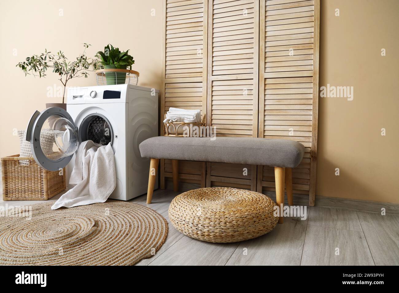 Laundry room interior with washing machine, grey bench and houseplants ...