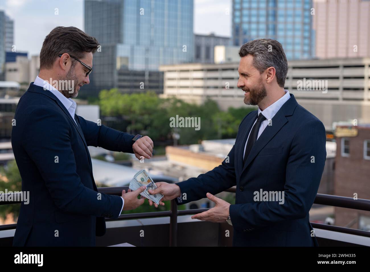 Businessman giving money to his partner outdoor. Businessman giving ...