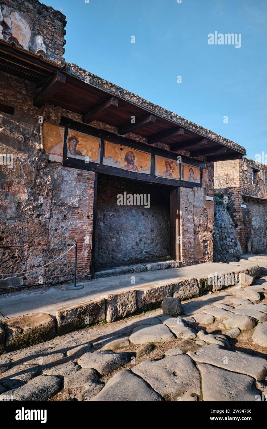 Naples, Italy - November 8 2023: Ancient shop and Painting of 4 Human Face Figures in the ...