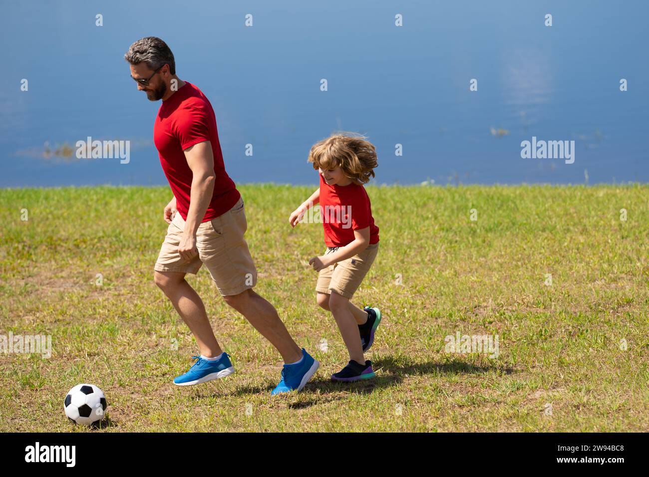Father and son enjoy a friendly game of football. Practice passing and ...