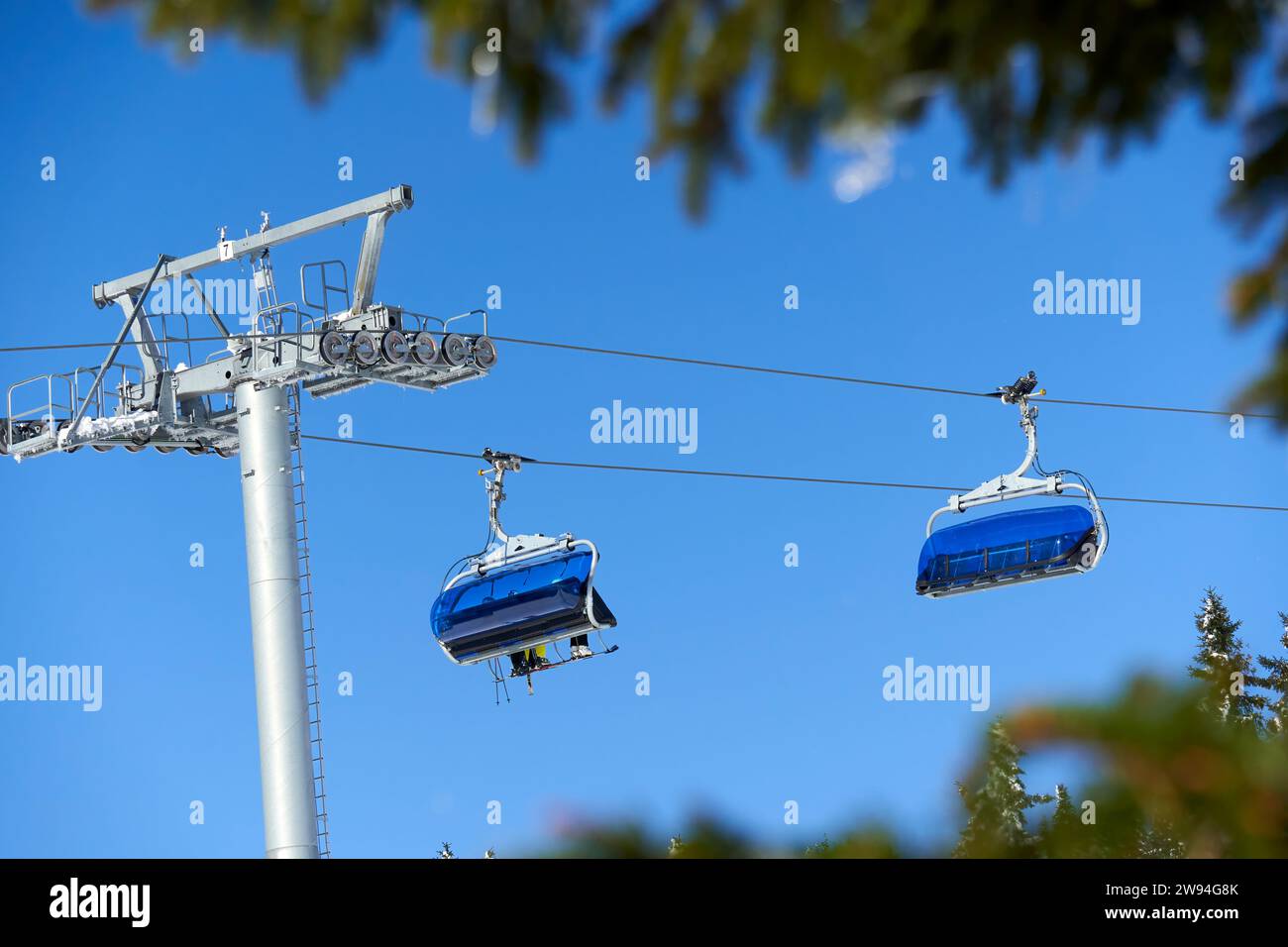 Chairlift of ropeway against blue sky. Cable car transports winter ski ...