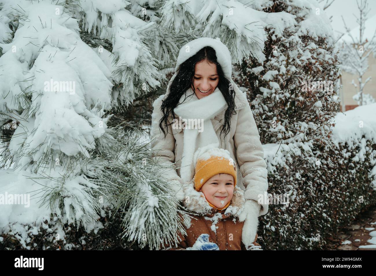 Happy funny moms with a child boy son playing in the park in the snow ...