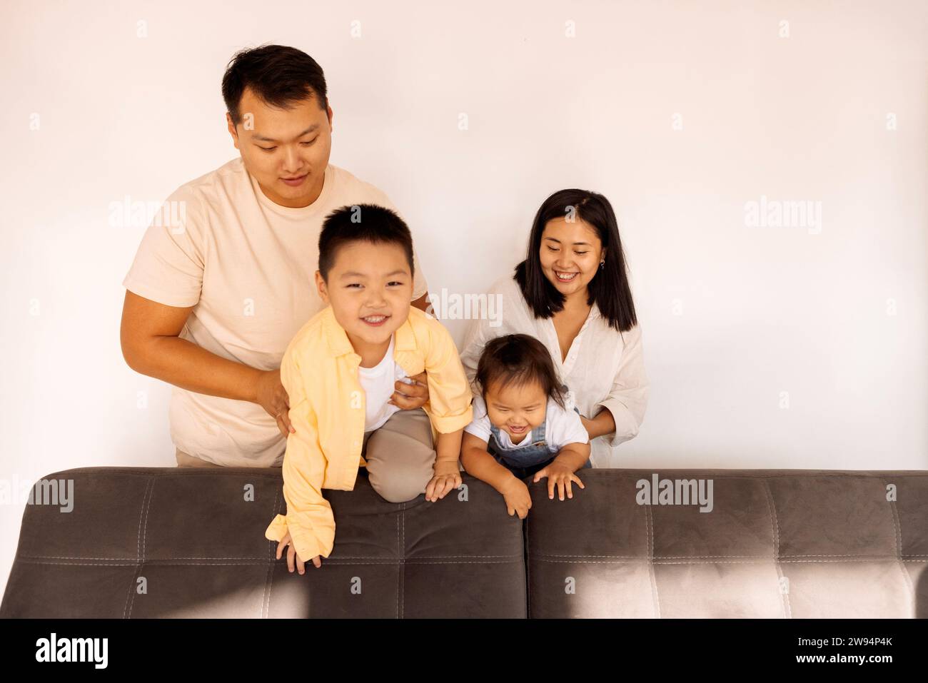 Happy Asian family at home. A Korean couple and their cute little kids ...