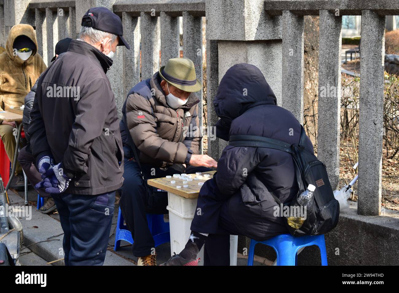 Old men playing janggi, Korean chess, with a spectator watching at the ...