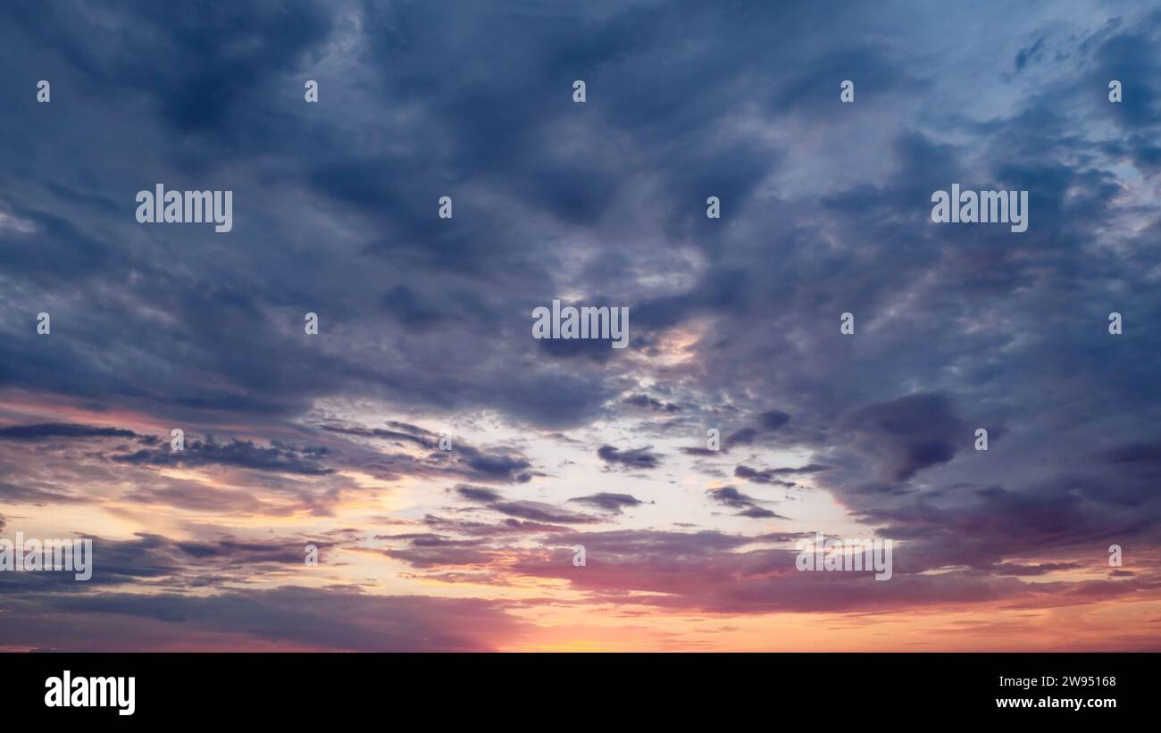 A pink and orange sunset with a cloudy sky, a blue hue, and a purple ...