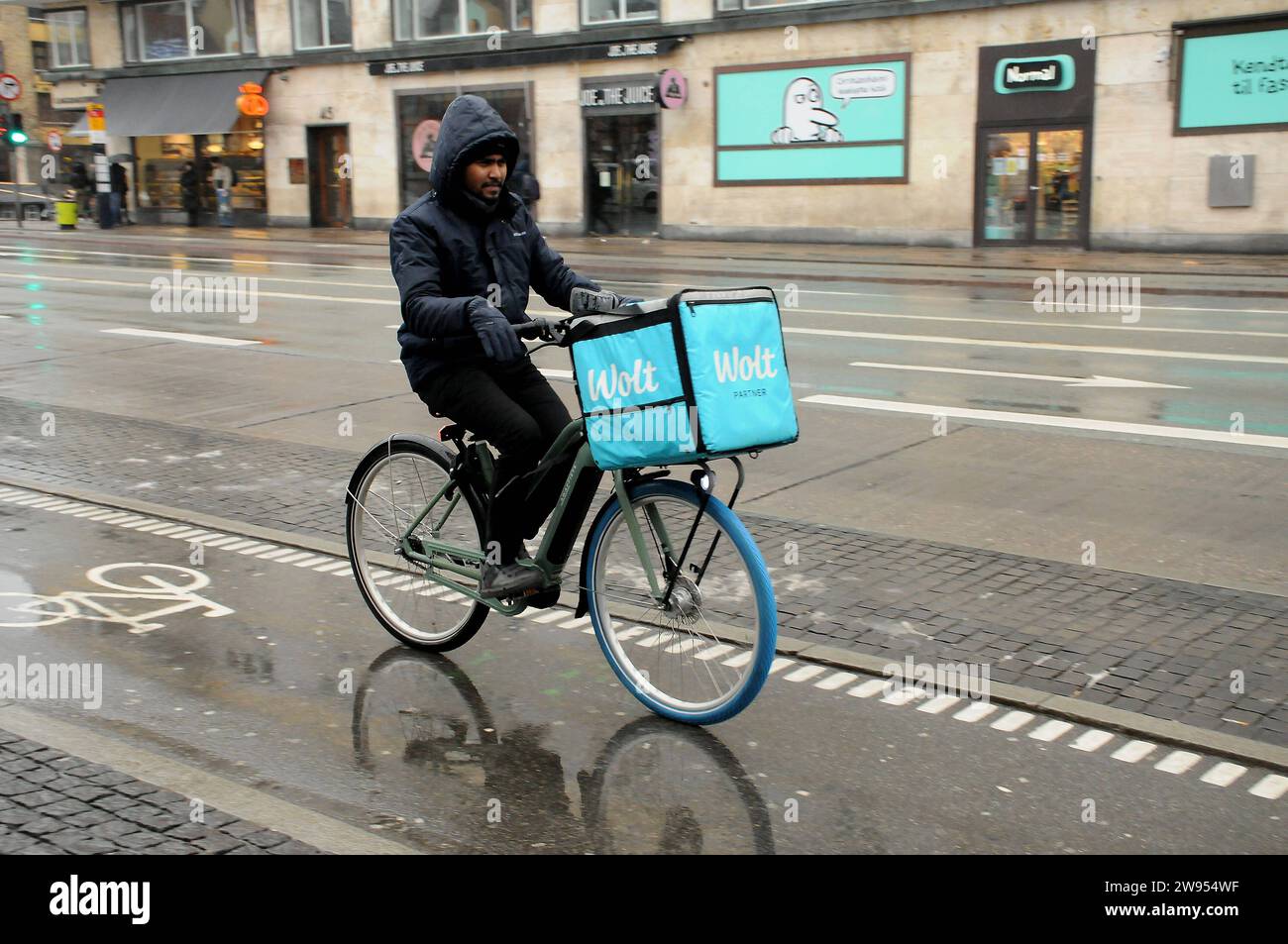 Copenhagen, Denmark /24 December 2023/. Wolt partner food delivery bikers and store in danish ...