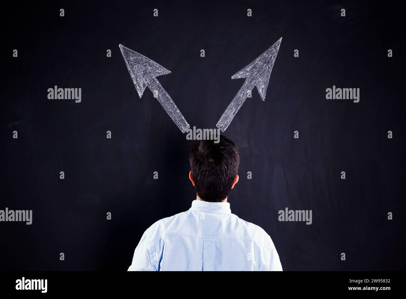 Businessman looking to a chalkboard with to arrows trying to decide one ...