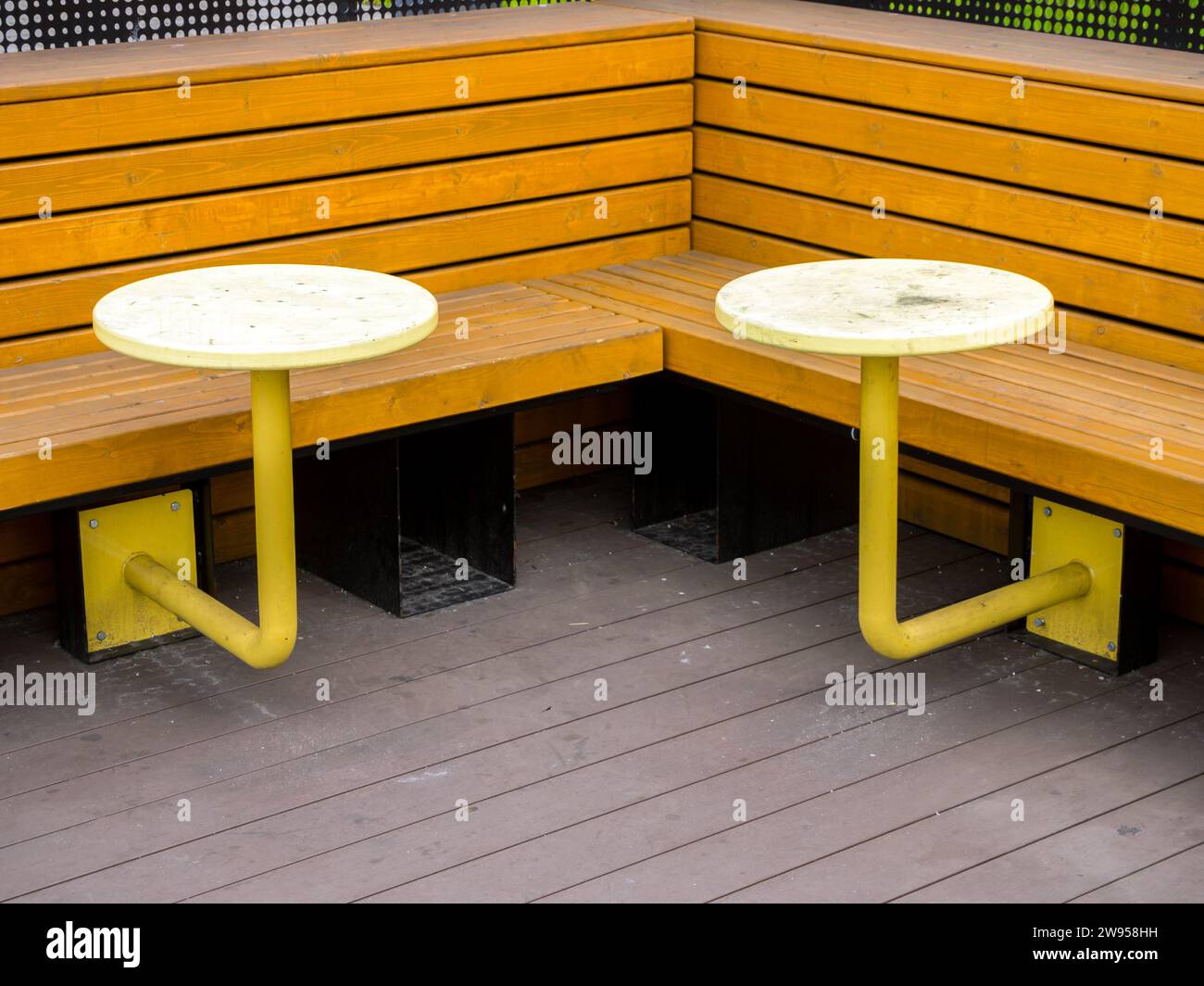 Corner bench with individual round metal tables Stock Photo - Alamy