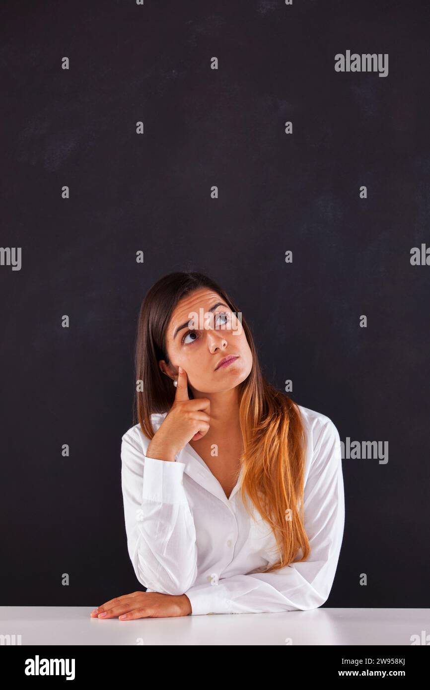 Woman thinking next to a blackboard Stock Photo - Alamy