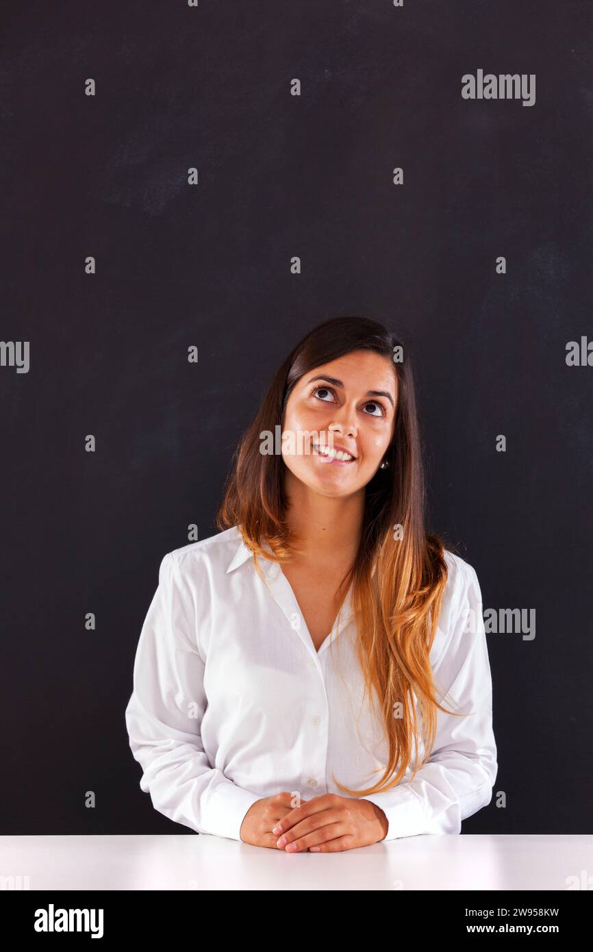 Woman thinking next to a blackboard Stock Photo - Alamy