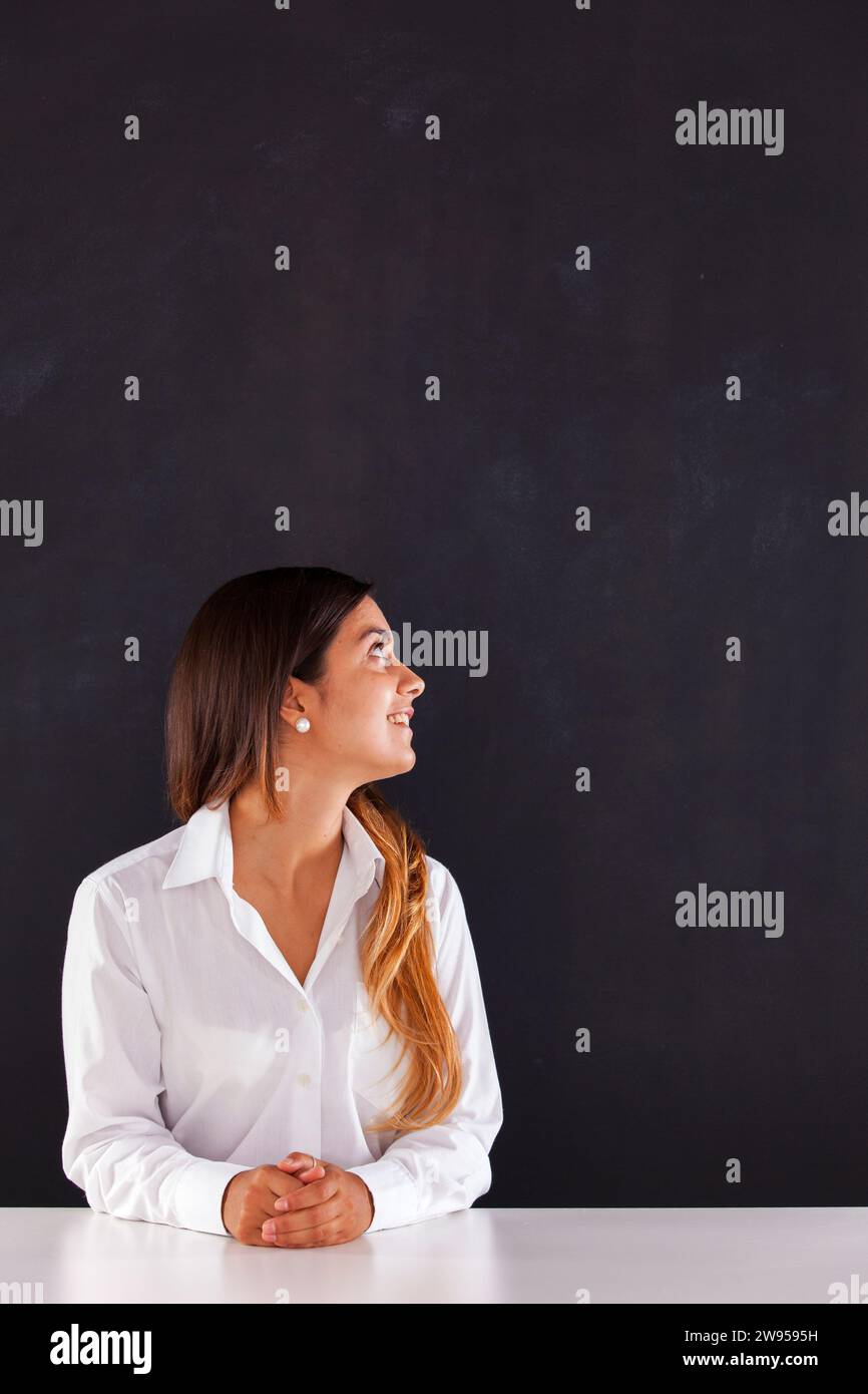 Woman thinking next to a blackboard Stock Photo - Alamy
