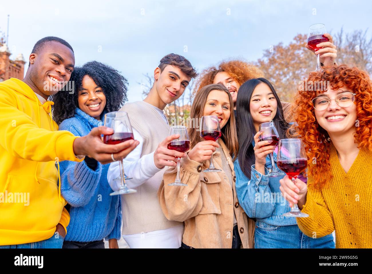 Students celebrating winter holidays with red wine in an urban park ...
