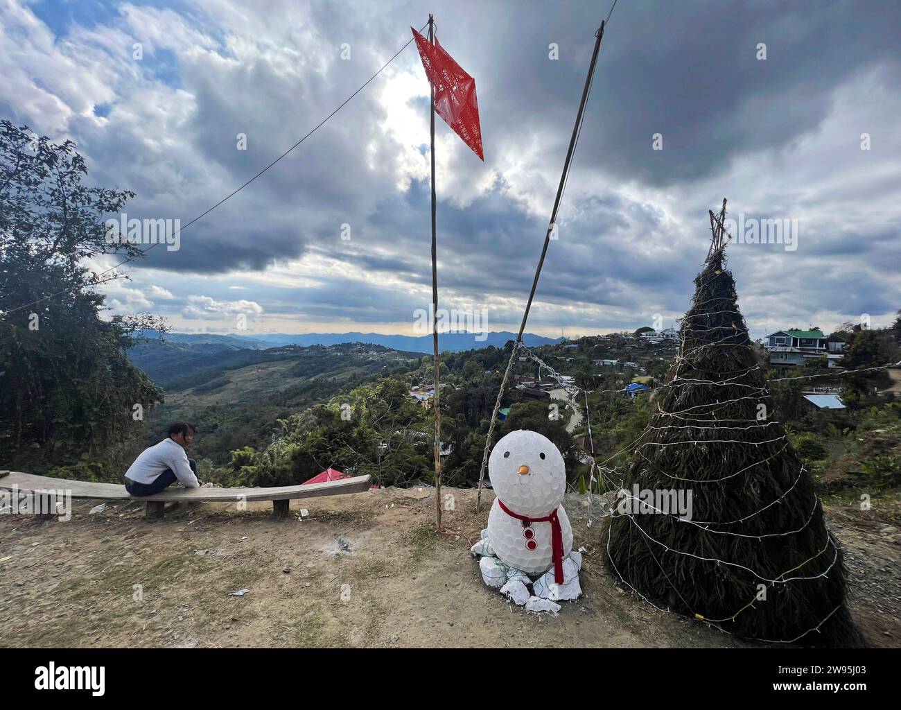 A Naga child sits on a bench next to a snowman made of recycled plastic ...