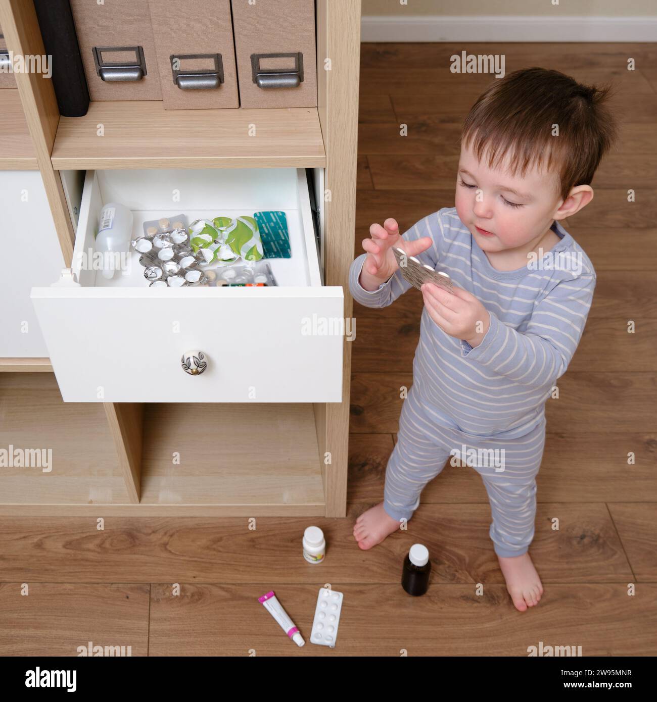 Toddler baby opened the cabinet drawer with pills and medicine. Child ...