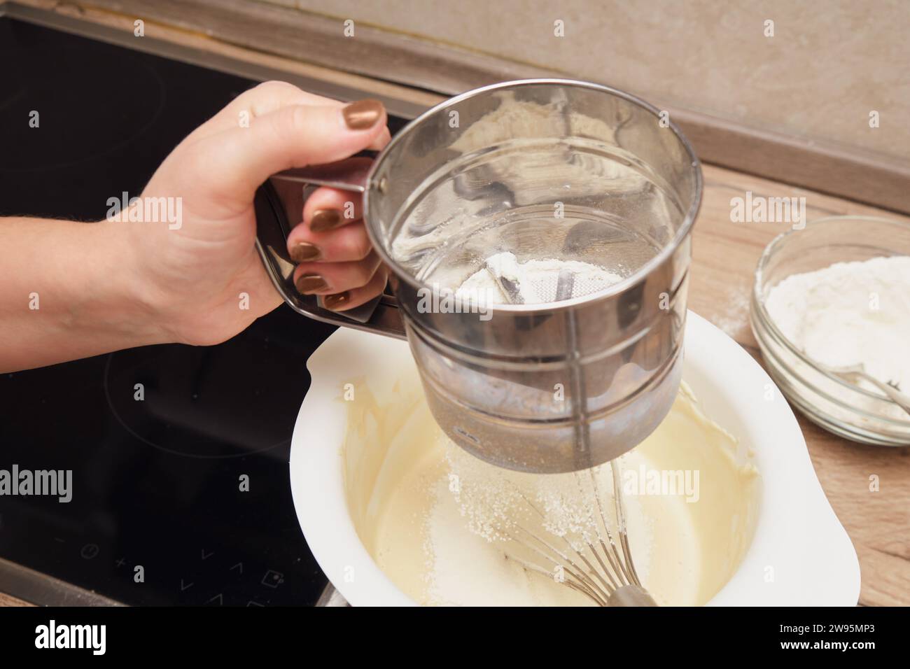 Female hands whisking flour into a bowl with a sieve, sifts flour Stock ...